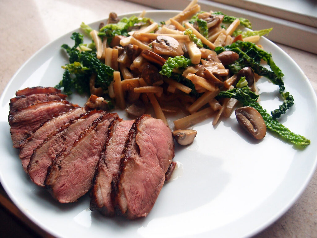 Stegt andebryst med varm salat af savoykål, brune champignoner og ...